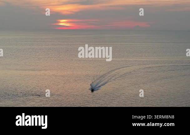A boat moves swiftly across the calm water while a parachute glider ...