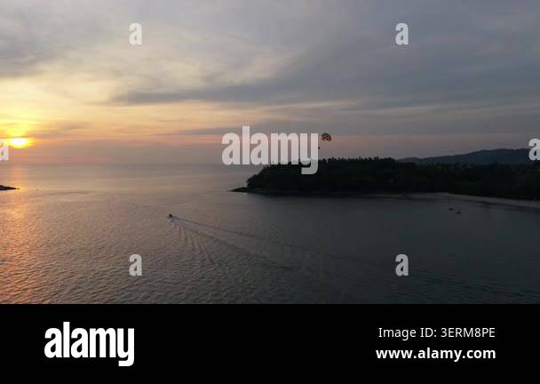 A parasail floats above the ocean as a boat moves steadily across the ...