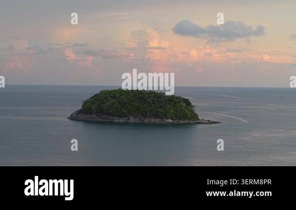 A tropical island with lush greenery is surrounded by calm ocean waters ...