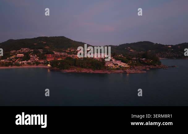 Aerial view of a coastal landscape at dusk, showcasing illuminated ...