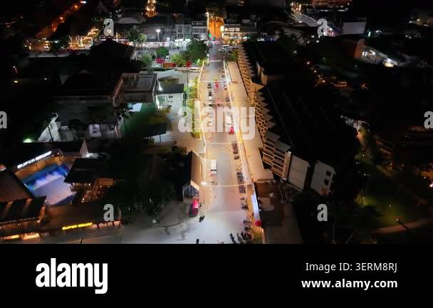 Aerial perspective of a brightly lit street featuring parked vehicles ...