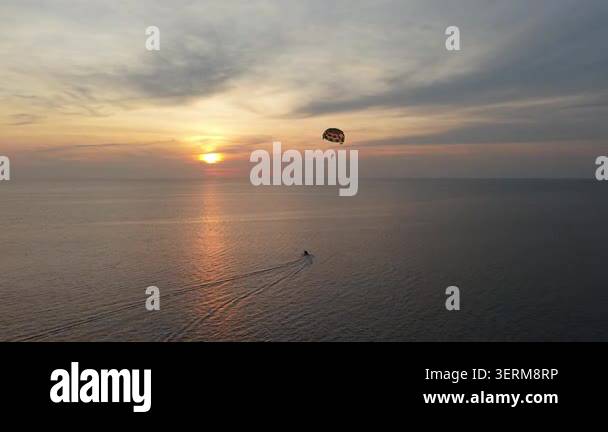 A parasailer is lifted into the air above the tranquil ocean during ...