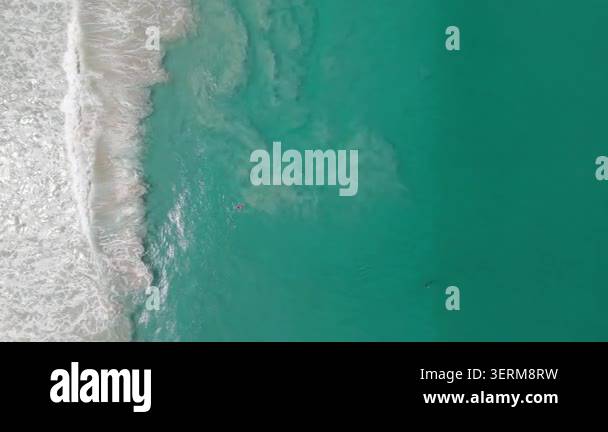 Aerial view of a swimmer in turquoise ocean water, surrounded by gentle ...