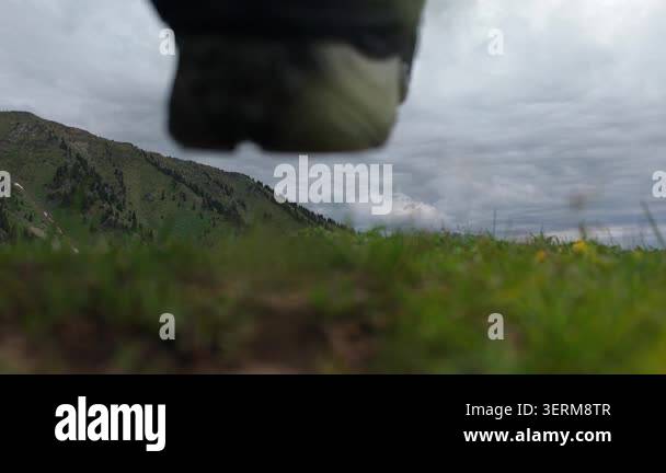 Individual in a red jacket walks away from the camera across a grassy ...