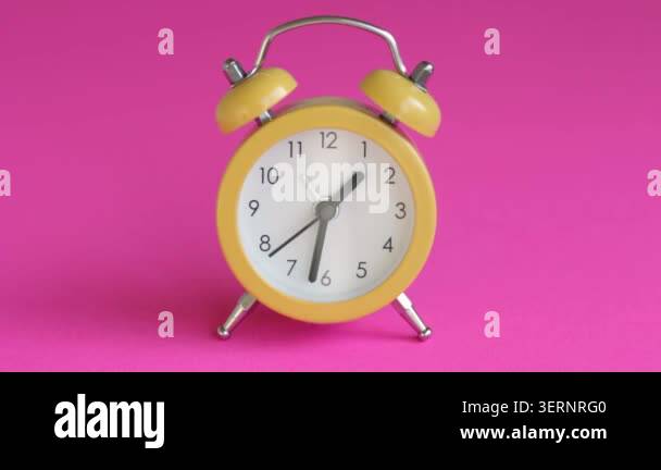 Yellow alarm clock on pink background close-up Stock Video Footage - Alamy
