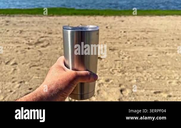 First-person view of a man's hand holding a reusable stainless steel ...