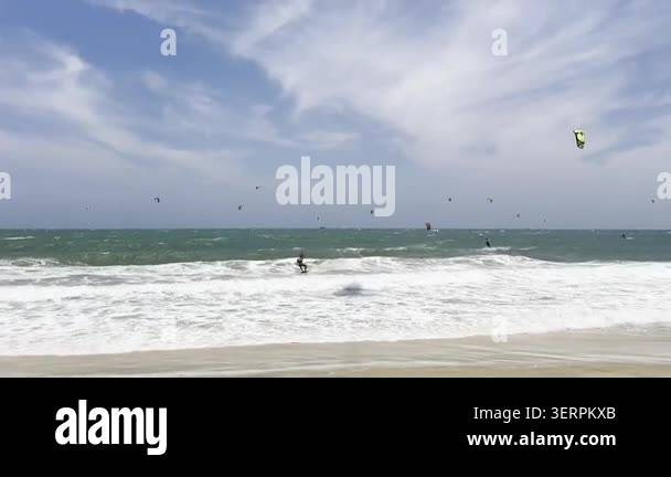 A dynamic coastal scene showing numerous kiteboarders catching waves on ...