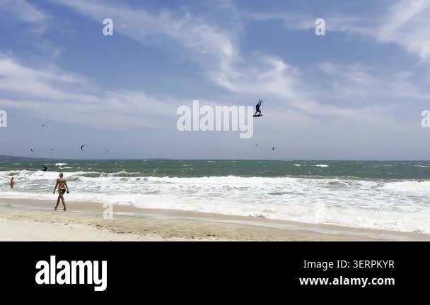 A dynamic coastal scene showing numerous kiteboarders catching waves on ...