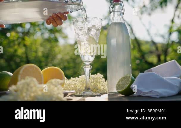 Homemade elderflower lemonade flowing from decorative bottle into ...