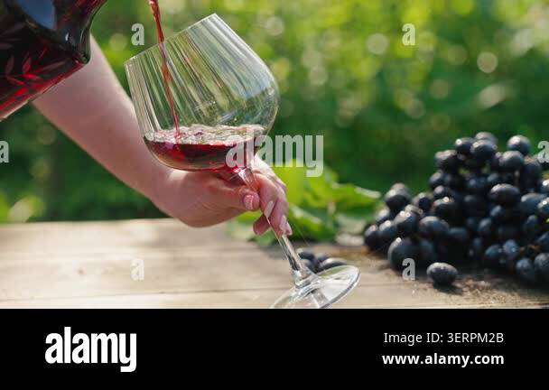 Close-up of red wine moving inside a large stemmed glass held outdoors ...
