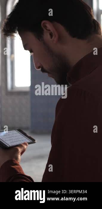 Back view of a Muslim bearded man sitting in a mosque reading the Quran ...
