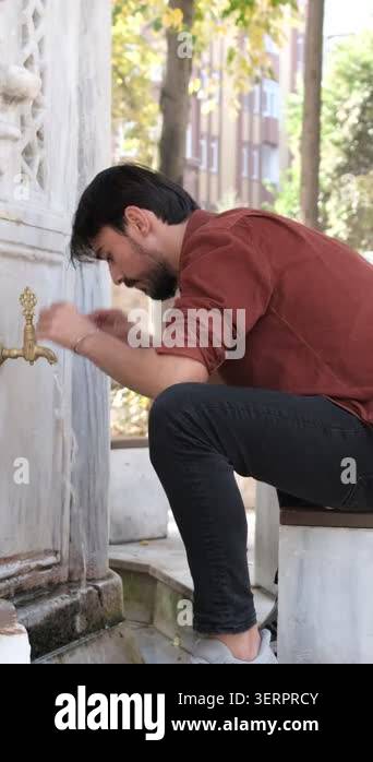 Young Muslim bearded man washing his nose while performing ablution at ...