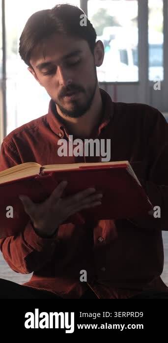 Bearded young man sitting in mosque studying Quran by looking at pages ...