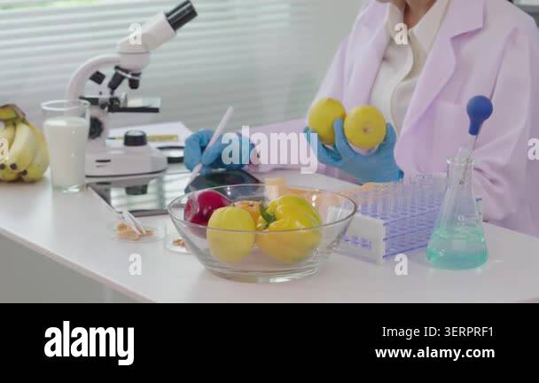 Side view of female Asian food scientist in lab coat and safety glasses ...