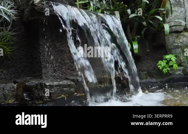 The video shows a small artificial cascading waterfall in a tranquil ...
