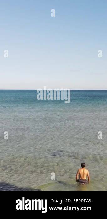 Aerial drone view shot of man in bright black swimming shorts on water ...