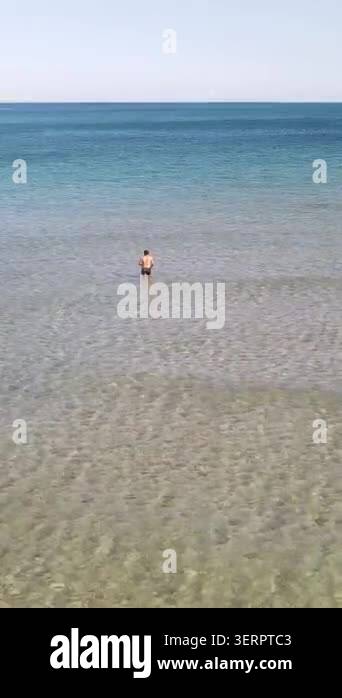 Aerial drone view shot of man in bright black swimming shorts on water ...