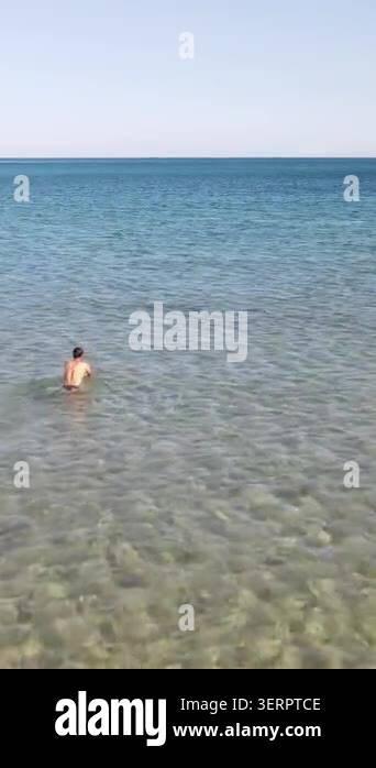 Aerial drone view shot of man in bright black swimming shorts on water ...