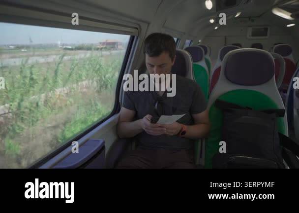 Young man traveling on an empty Italian train with colorful seats using ...
