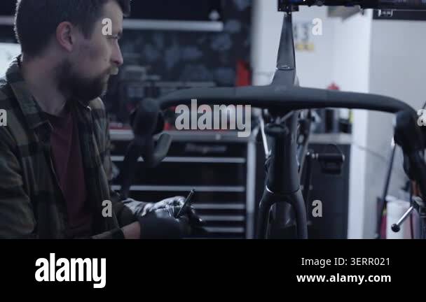 Focused male mechanic fixing expensive black carbon road bike in ...