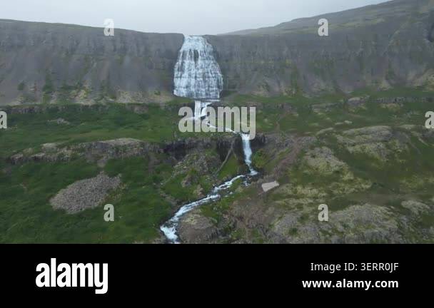 Aerial flight over the beautiful and wide sweeping waterfall Dynjandi ...