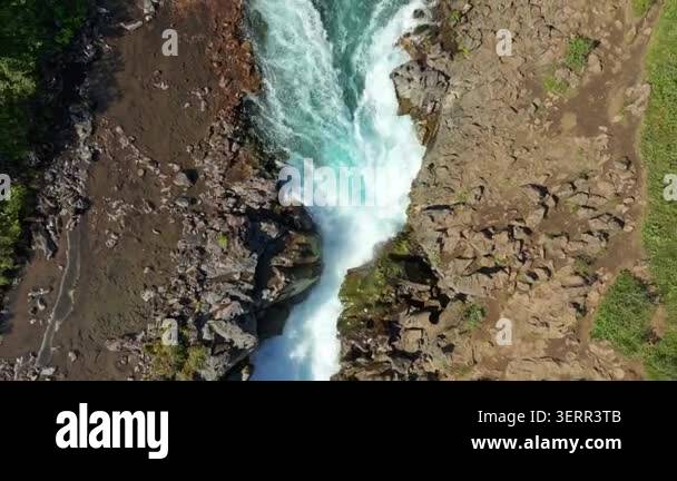 Aerial flight over the wild foamy Hlauptungufoss waterfall on a summer ...