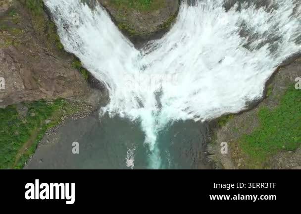 Aerial flight over the beautiful Hjalparfoss waterfall on a summer day ...