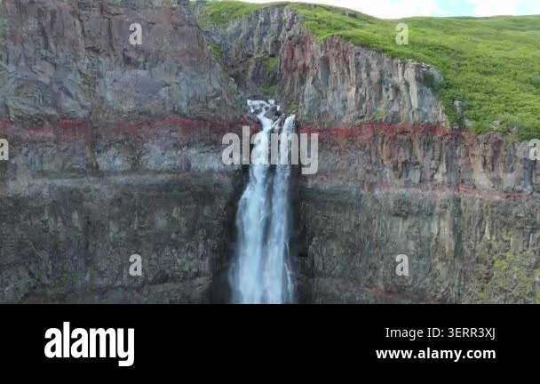 Aerial flight over the Lambagilsfoss waterfall on a summer day located ...