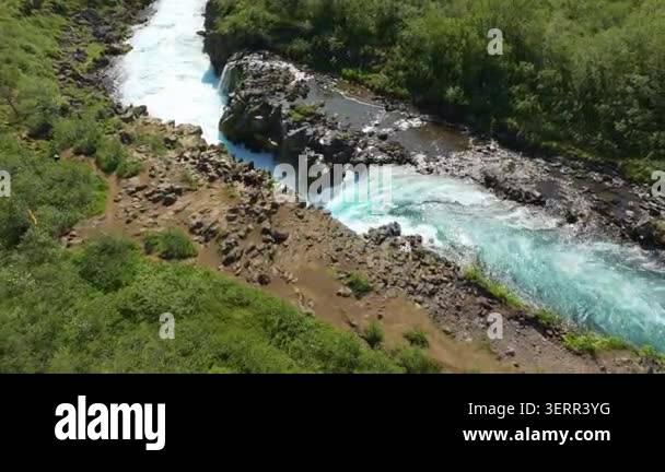 Aerial flight over the wild foamy Hlauptungufoss waterfall on a summer ...