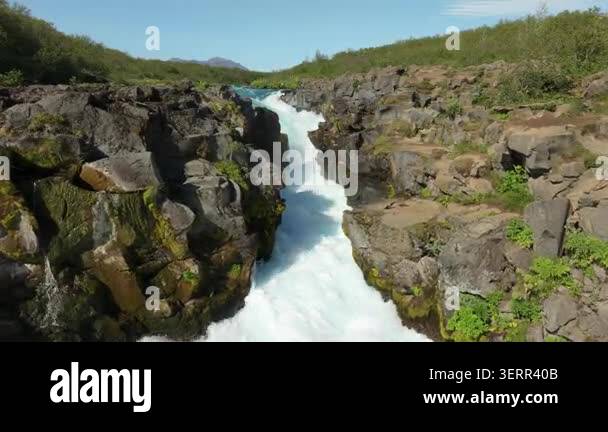 Aerial flight over the wild foamy Hlauptungufoss waterfall on a summer ...