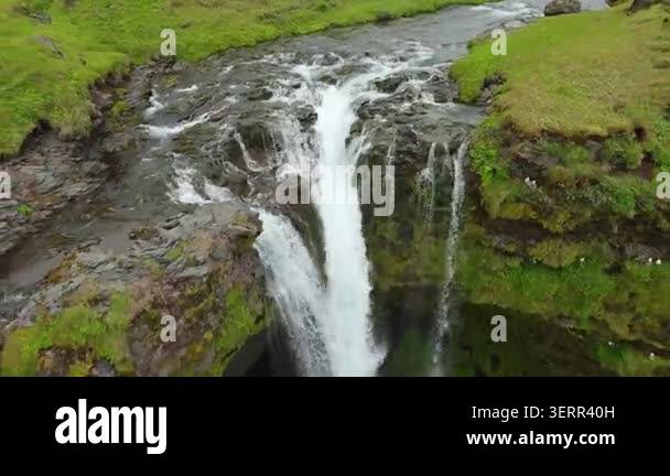 Aerial flight over the beautiful Kvernufoss waterfall on a summer day ...