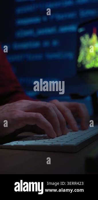 Close-up of a male coder hands typing on a keyboard in a dark high-tech ...