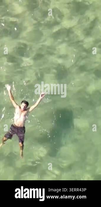 Aerial drone view shot of man in bright black swimming shorts on water ...
