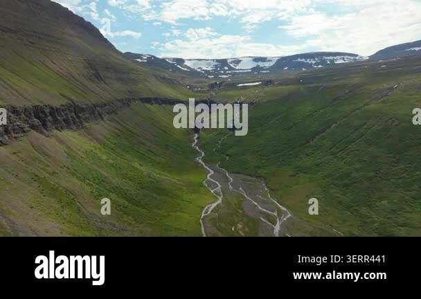 Aerial flight over a green valley with rivers and waterfalls on a ...