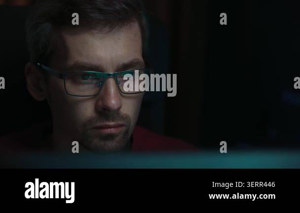 Portrait of a male software engineer stares with deep focus, working on ...