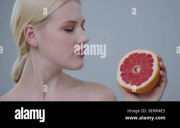 Cheerful blonde model holding a half of grapefruit instead of an eye ...