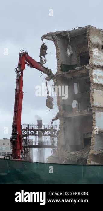 Long reach excavator demolishing old brick apartment building, breaking ...