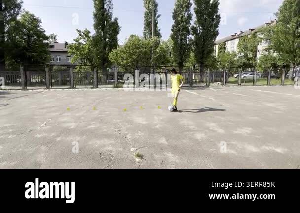 Teen boy running with football ball and shooting into goal on outdoor ...
