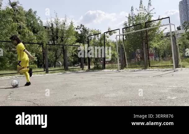 Teen boy kicking football ball towards goal on outdoor court youth ...