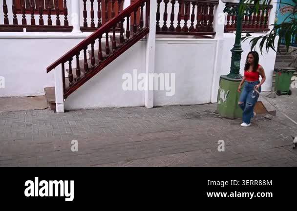 Young woman walking a xoloitzcuintli dog on a leash in a residential ...