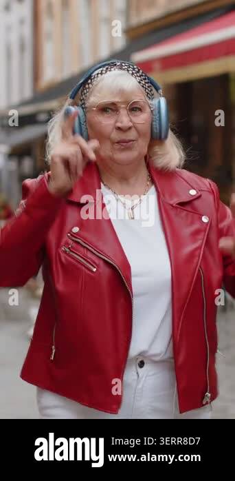 Happy overjoyed senior woman in wireless headphones listening favorite ...