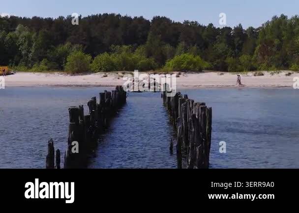 Aerial shot shows weathered wooden groyne rows leading to sandy shore ...