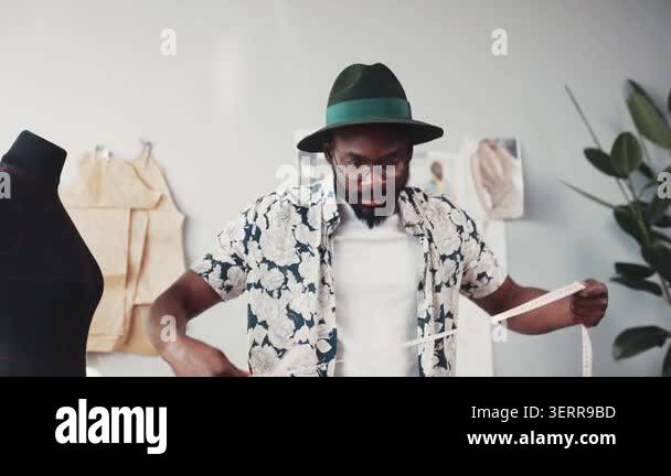 Confident, stylish tailor in trendy look puts measuring tape around his ...