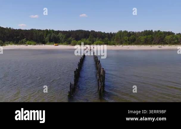 Aerial glide over Jurmala, Latvia shows wooden groynes, rocky jetty ...