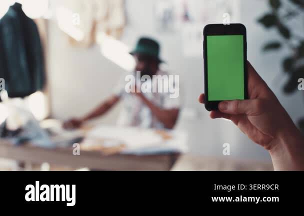 Male hand holds the smartphone with green screen, takes photo of a busy ...