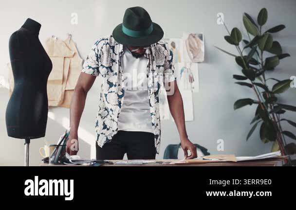 Handsome Afro-American man in a hat checks the result of his design ...