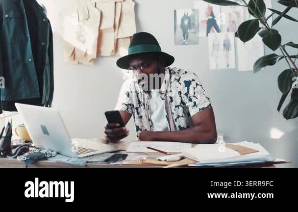 Cool designer uses his smartphone. Comfortable office with fashion ...