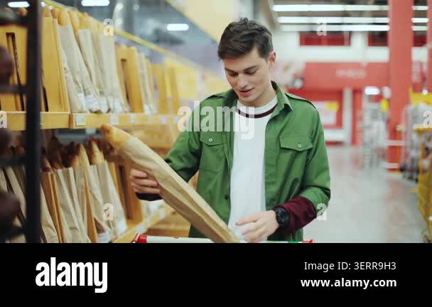 A young handsome man in a supermarket buy baguette smiling bakery food ...