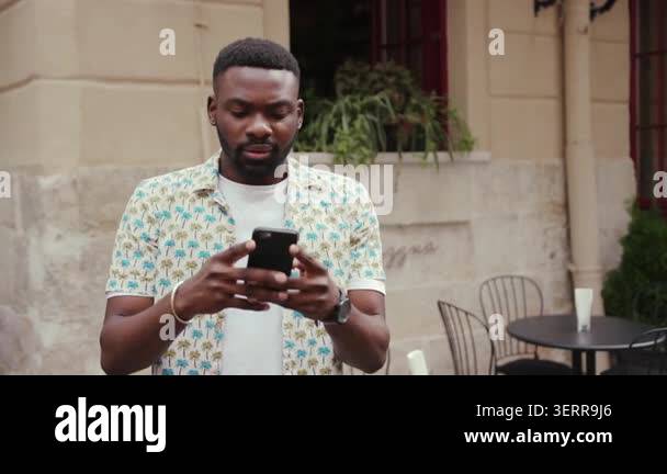 Likable young man with mobile phone in hands looking right at screen ...