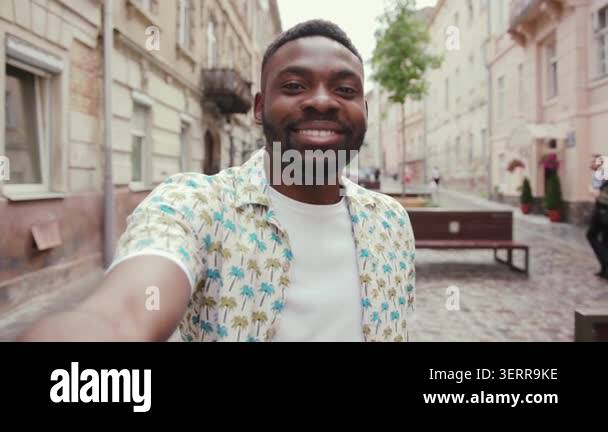 Close-up of young optimistic African man walking down the street with ...